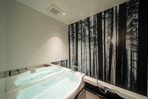 Um banheiro com uma banheira grande, um espelho e um mural na parede com tema florestal.