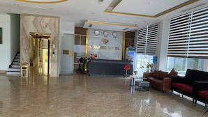 Um saguão de hotel com balcão de recepção, escada e área de estar.