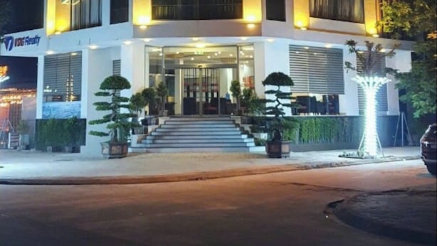 Um hotel moderno com um letreiro de neon chamativo, vários andares e uma entrada bem iluminada.