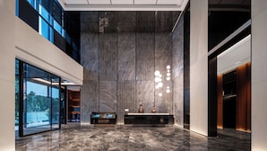 Um lobby moderno com uma receção, amplas janelas e chão de mármore.