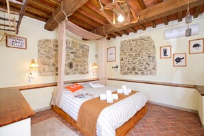 Quarto com parede de pedra, cama com colcha listrada e uma placa na parede.