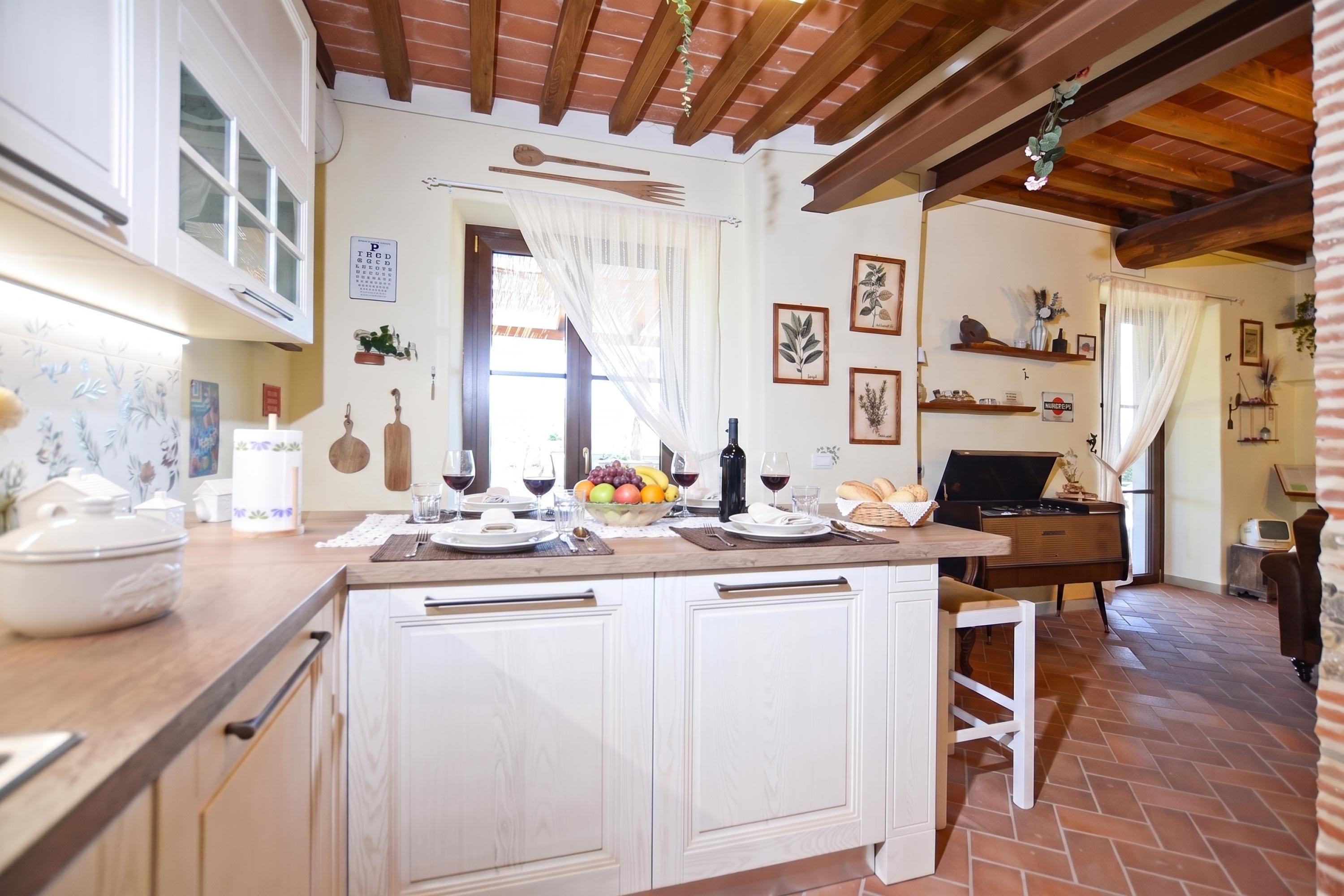 Cozinha com ilha central, armários de madeira e chão de tijolos.