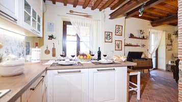 Cozinha com ilha central, armários de madeira e chão de tijolos.