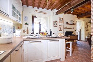 Cozinha com ilha central, armários de madeira e chão de tijolos.