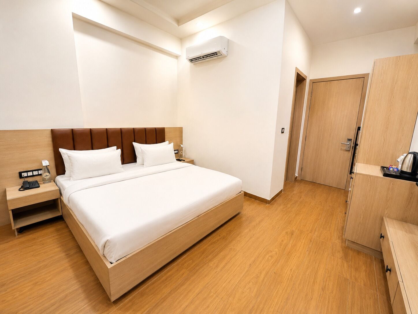 Quarto de hotel com uma cama, mesa de cabeceira, guarda-roupa e ar condicionado.