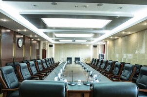 Uma sala de conferência com uma mesa comprida, várias cadeiras e um design moderno no teto.