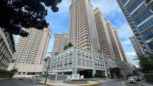Um edifício alto com várias varandas, um pátio central com estátuas e céu claro.