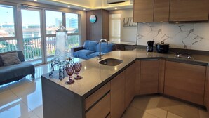 Uma cozinha moderna com uma ilha central, armários de madeira e uma grande janela com vista para uma varanda.