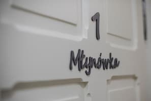 Uma porta branca com o número 1 e o nome 'Mtynowka' numa fonte de estilo caligráfico.