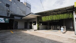 Um edifício com entrada coberta, uma placa com texto e uma área de estacionamento.