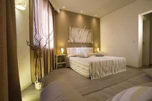 Quarto com cama, abajures, uma obra de arte na parede e um vaso com galhos.