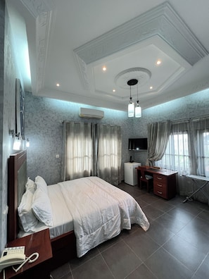 Quarto de hotel com cama, escrivaninha, cadeira, penteadeira e televisão de tela plana.