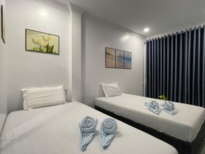 Quarto de hotel com duas camas, janela com cortinas e obras de arte nas paredes.