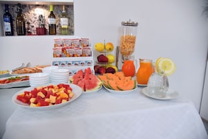 Um buffet de café da manhã com diversas frutas, cereais e bebidas.