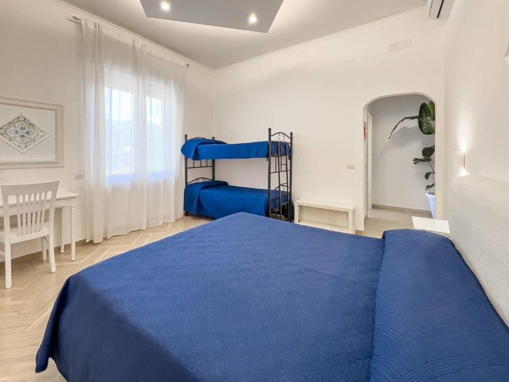 Quarto com beliches, uma escrivaninha e uma cadeira.