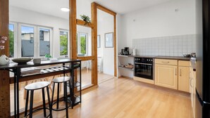 Cozinha moderna com vigas de madeira, área de jantar com banquetas e vista através de grandes janelas.