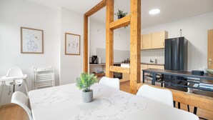 Uma cozinha moderna com vigas de madeira, uma mesa de jantar de mármore e um vaso com planta.