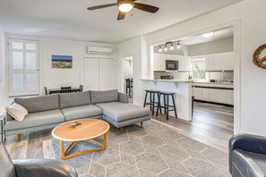 Uma sala de estar moderna com um sofá modular, uma mesa de centro redonda e um ventilador de teto.