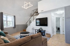 Uma sala de estar moderna com escada, televisão de tela plana e um espaço de estar aconchegante.