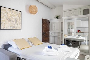 Quarto de hotel com cama, escrivaninha, cadeira, espelho e guarda-roupa.