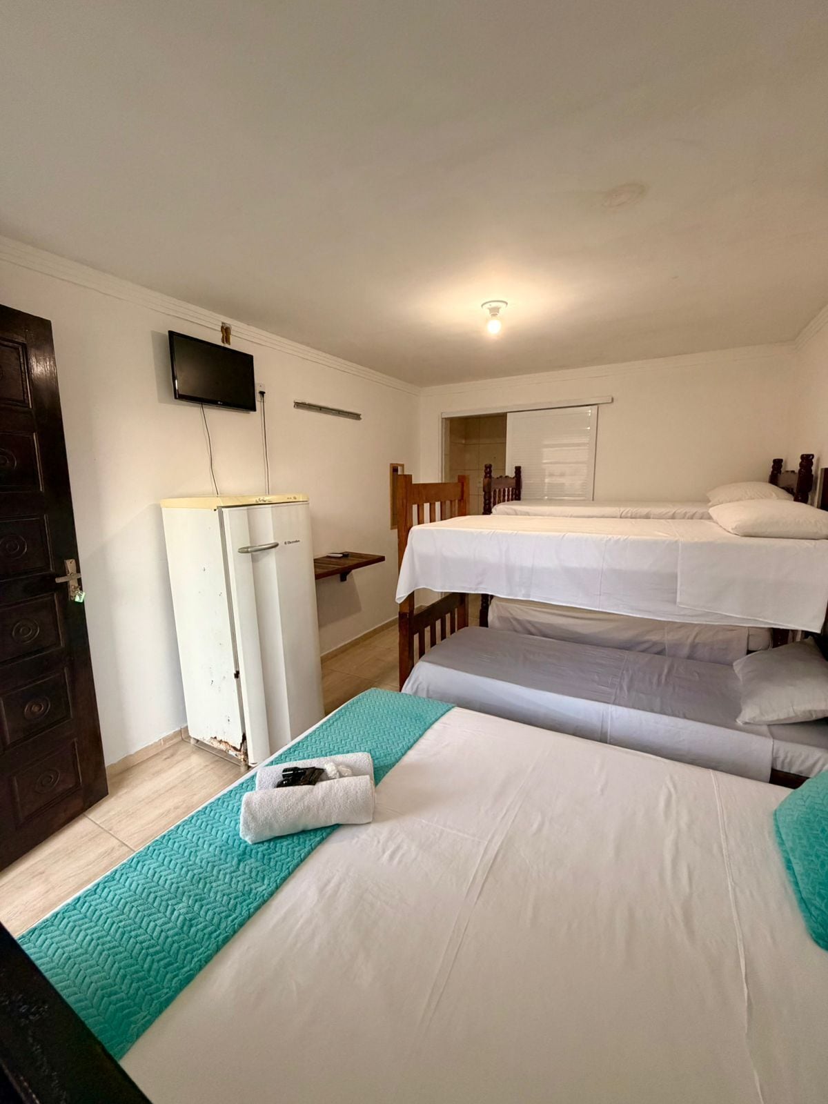 Quarto com duas camas, televisão, guarda-roupa e secretária.