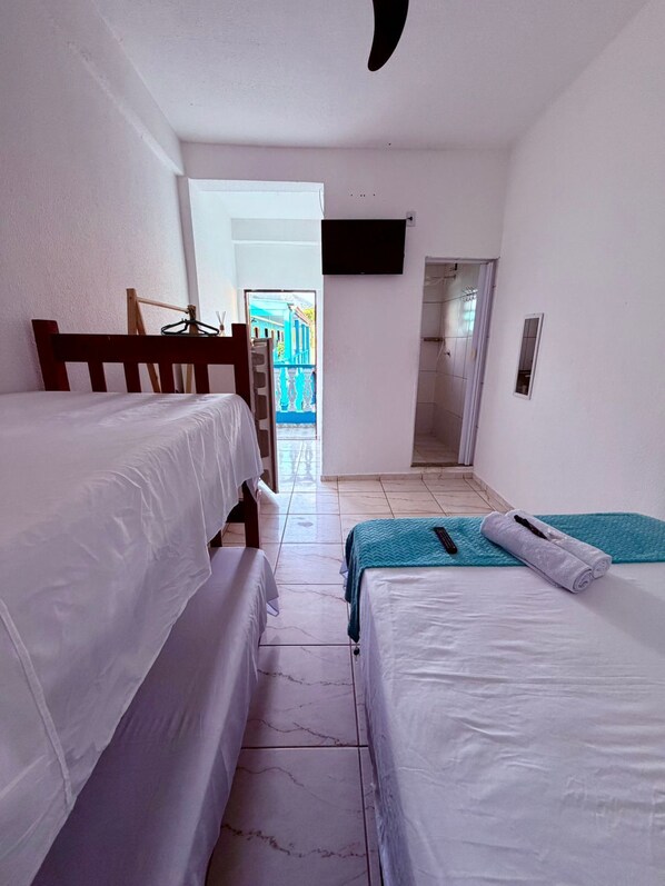 Quarto de hotel com duas camas, televisão, chuveiro e vista para o exterior.