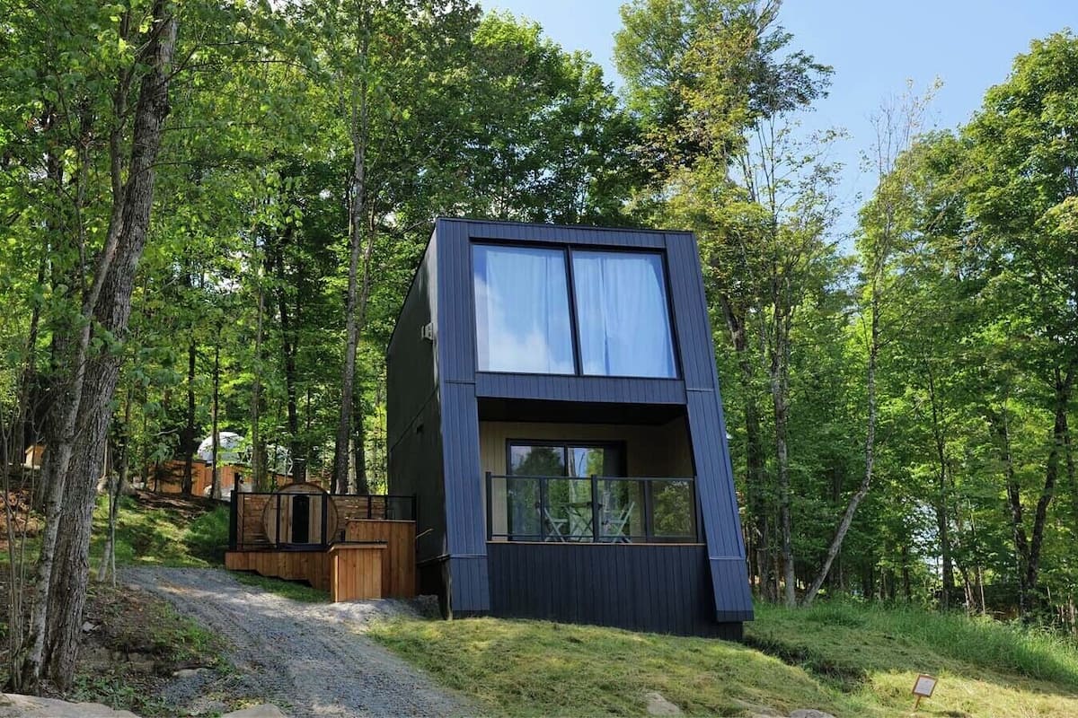 Uma cabana moderna com uma janela grande, rodeada por árvores.