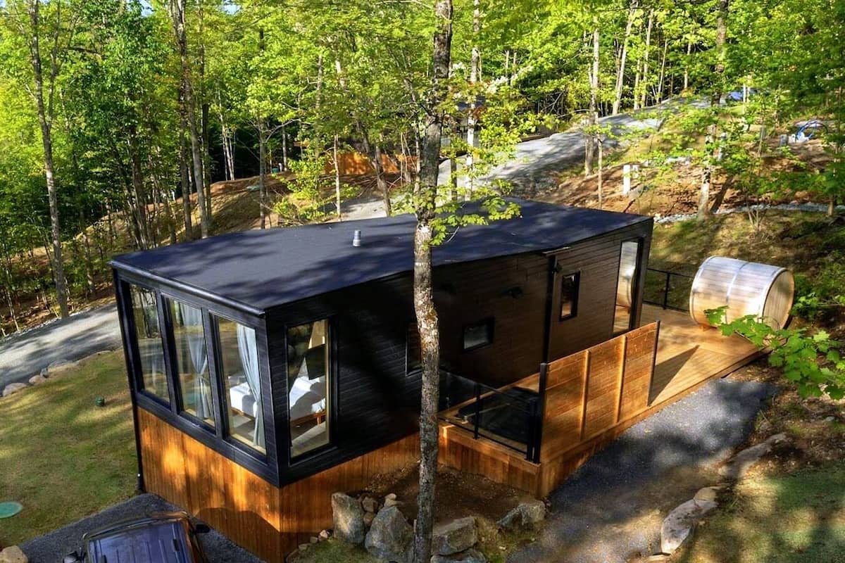 Uma cabana com fachada de vidro, exterior de madeira e uma pequena área de deck.