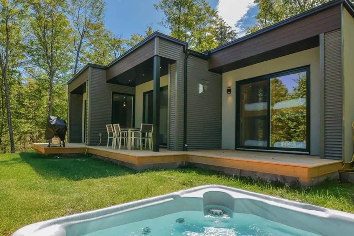 Uma casa moderna com hidromassagem, um pátio com cadeiras e uma grande porta de vidro deslizante.