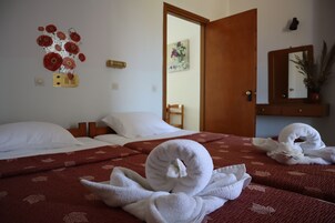 Quarto de hotel com duas camas, uma porta de madeira, um espelho e um adorno na parede.