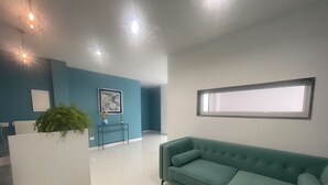 Uma sala de estar moderna com um sofá verde-água, uma mesa consola branca e um quadro na parede.