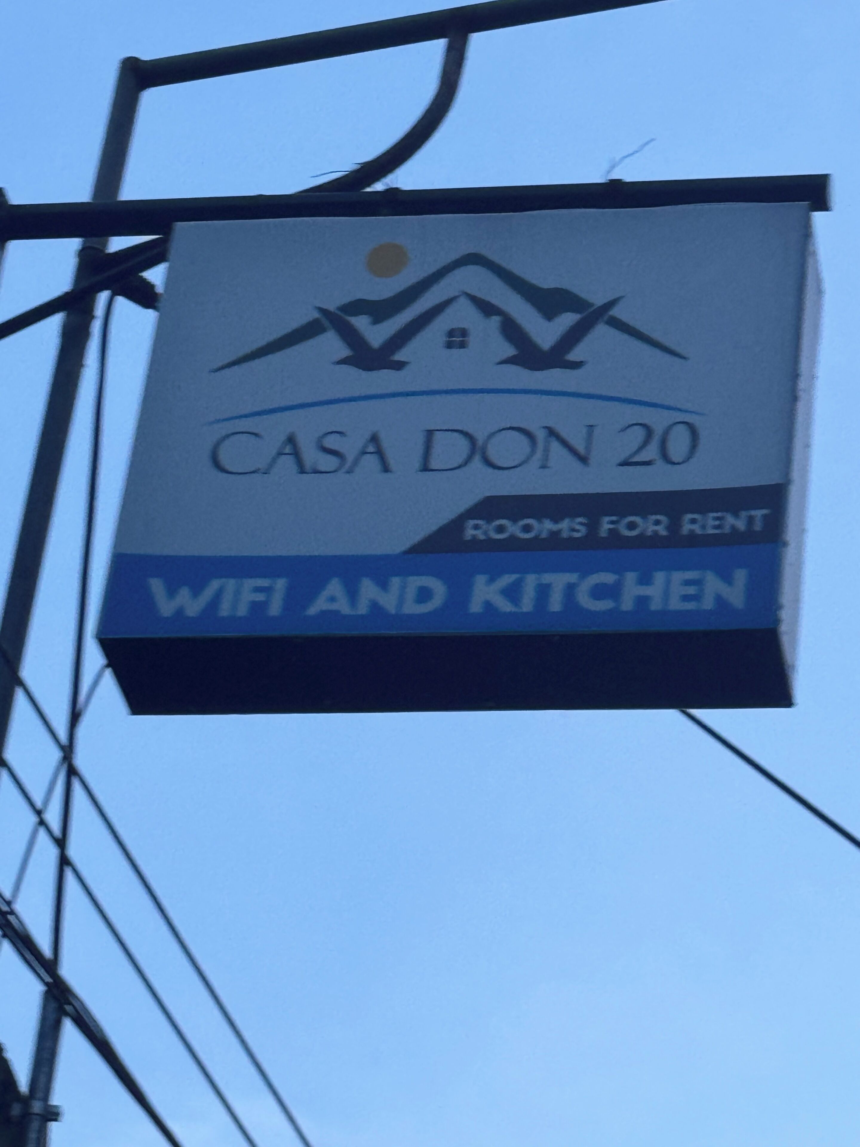 Placa anunciando 'Casa Don 20', com quartos para alugar e comodidades como WiFi e acesso à cozinha.