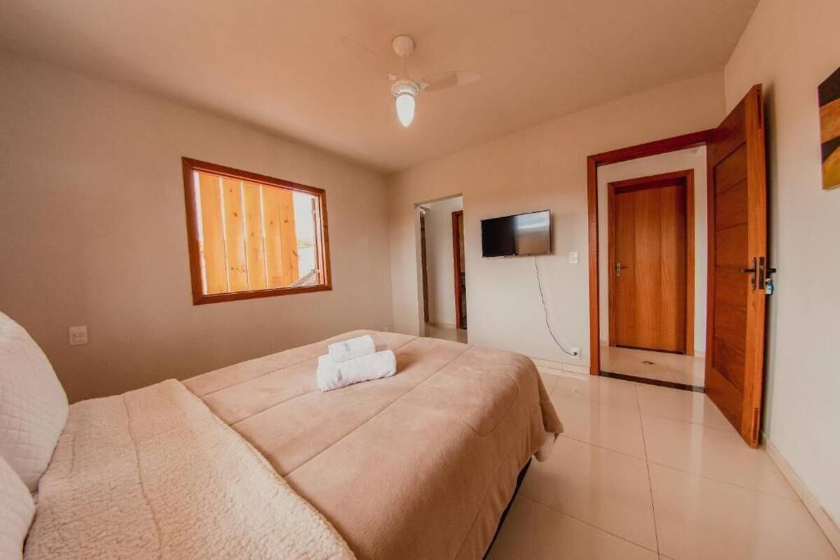 Quarto com cama, televisão na parede e uma porta.