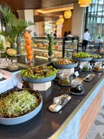 Um buffet com diversos itens alimentares, incluindo saladas, frutas e acompanhamentos.