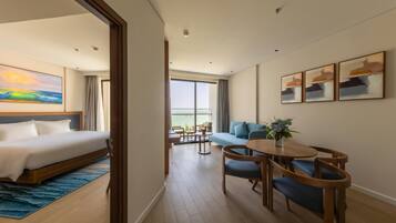 Quarto de hotel com cama, sofá, mesa de jantar com cadeiras e obras de arte nas paredes.
