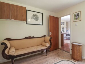 Uma sala de estar com sofá, porta de madeira e um quadro na parede.
