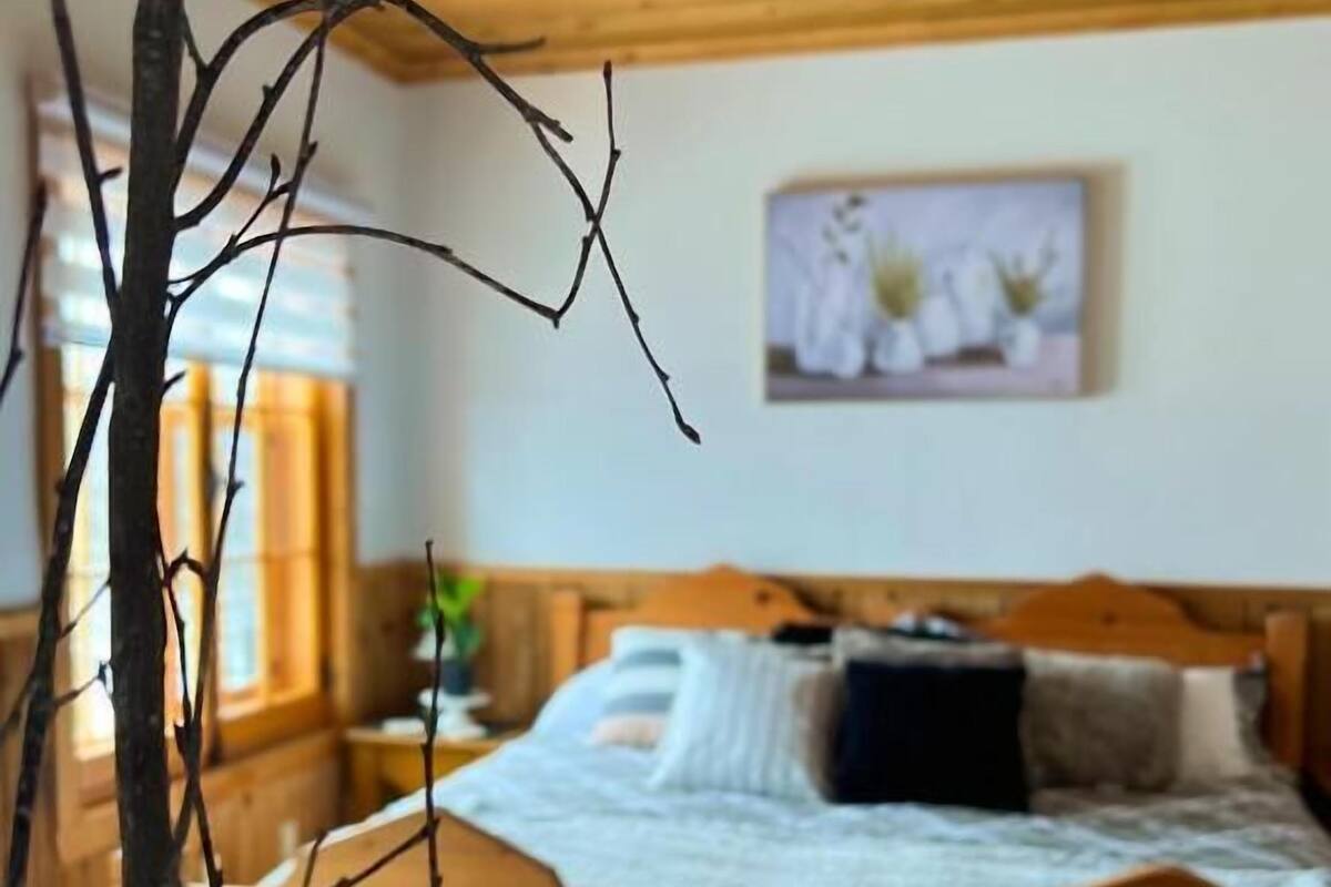 Uma cama de madeira com cabeceira, mesa de cabeceira e um quadro pendurado na parede.