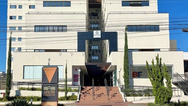 Um hotel moderno com entrada central, vários andares e um letreiro chamativo.