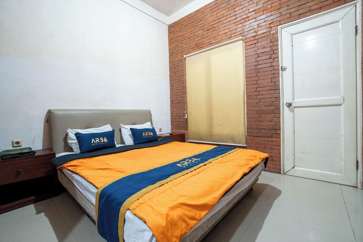 Um quarto com cama, mesa de cabeceira, guarda-roupa e porta.