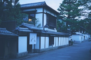 Um edifício japonês tradicional com telhado de telhas, vigas de madeira e uma rua estreita.