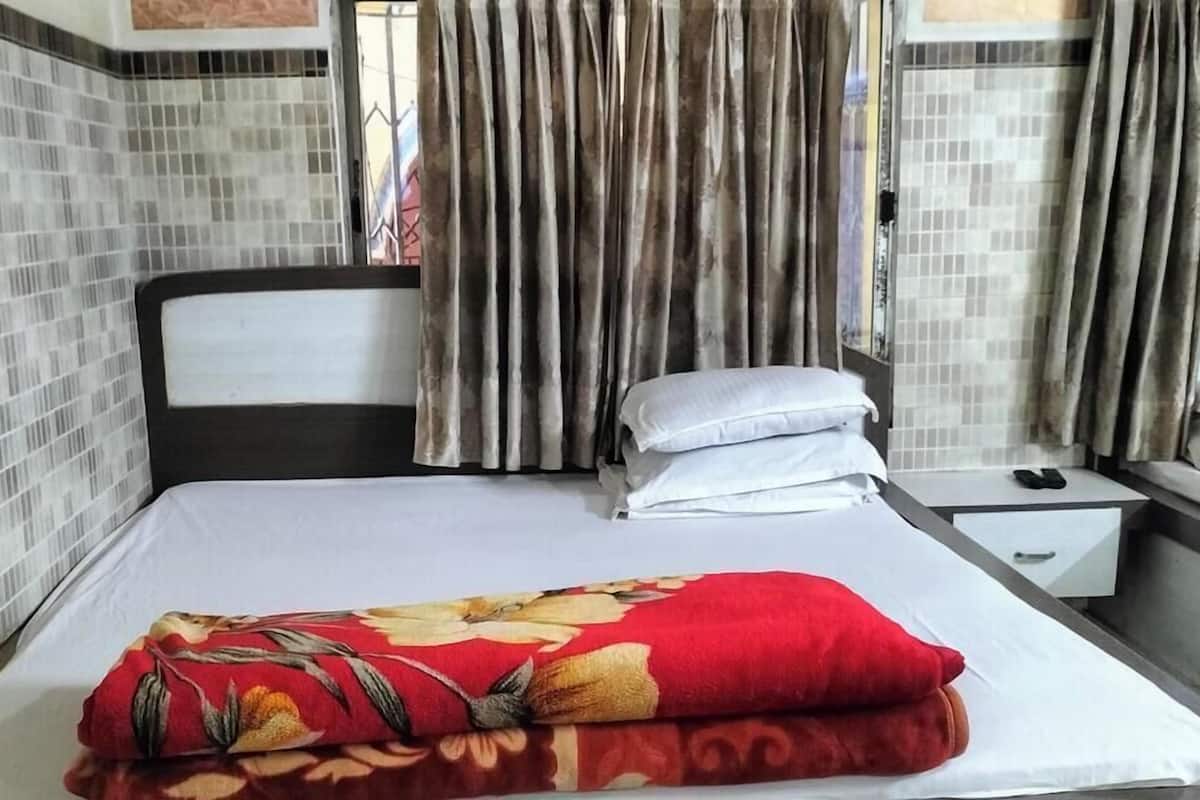 Quarto de hotel com uma cama, mesa de cabeceira, espelho e cortinas.