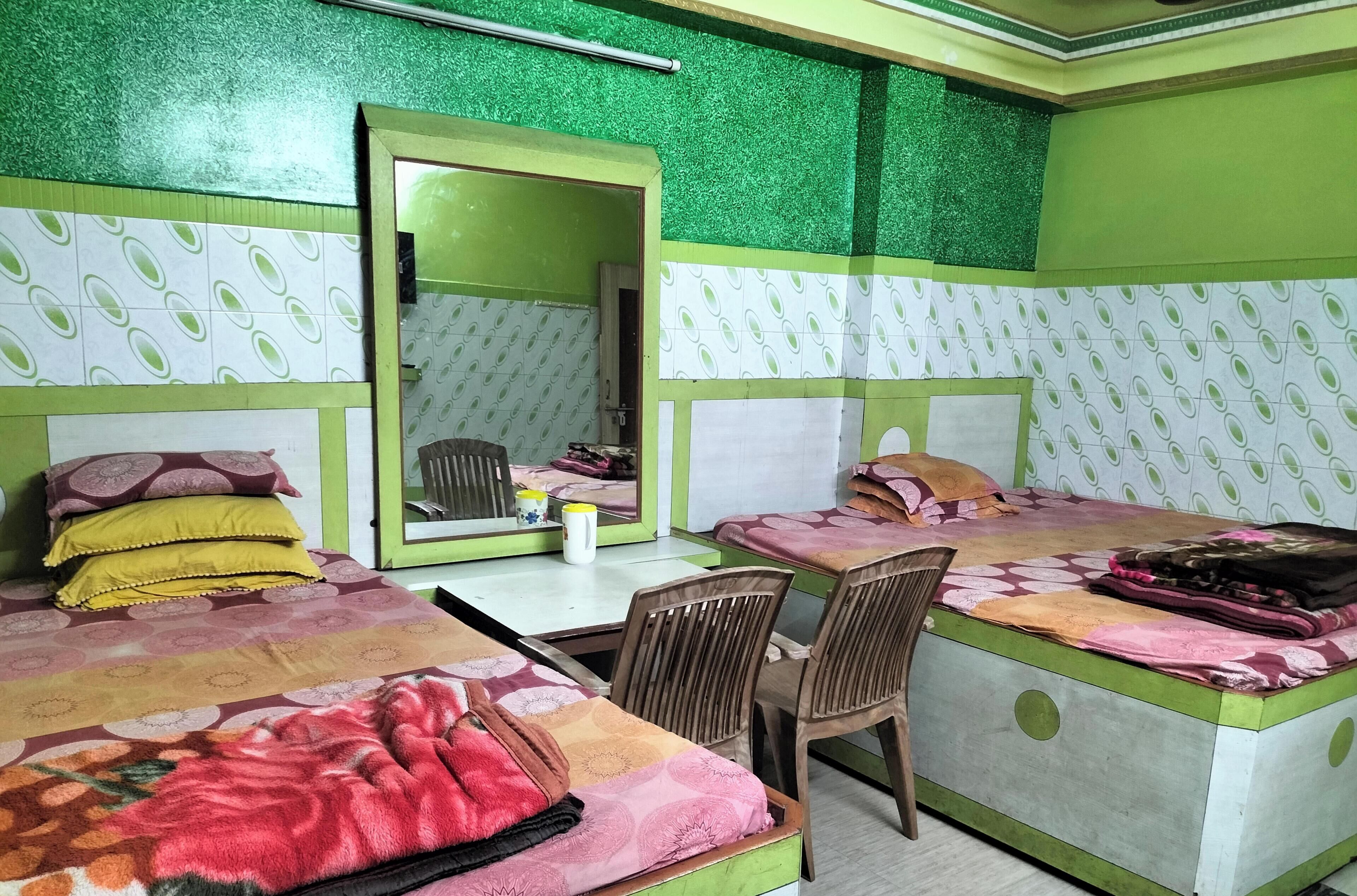 Quarto com duas camas, uma cadeira, uma mesa e um espelho.