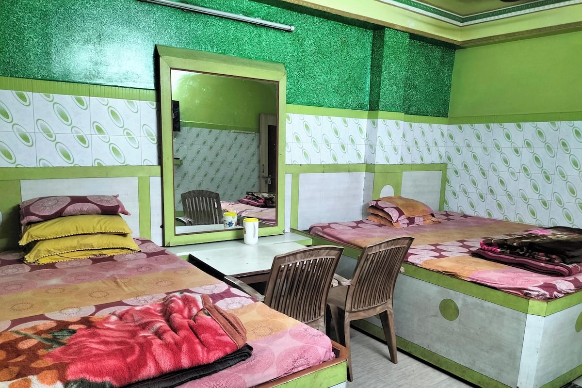 Quarto com duas camas, uma cadeira, uma mesa e um espelho.