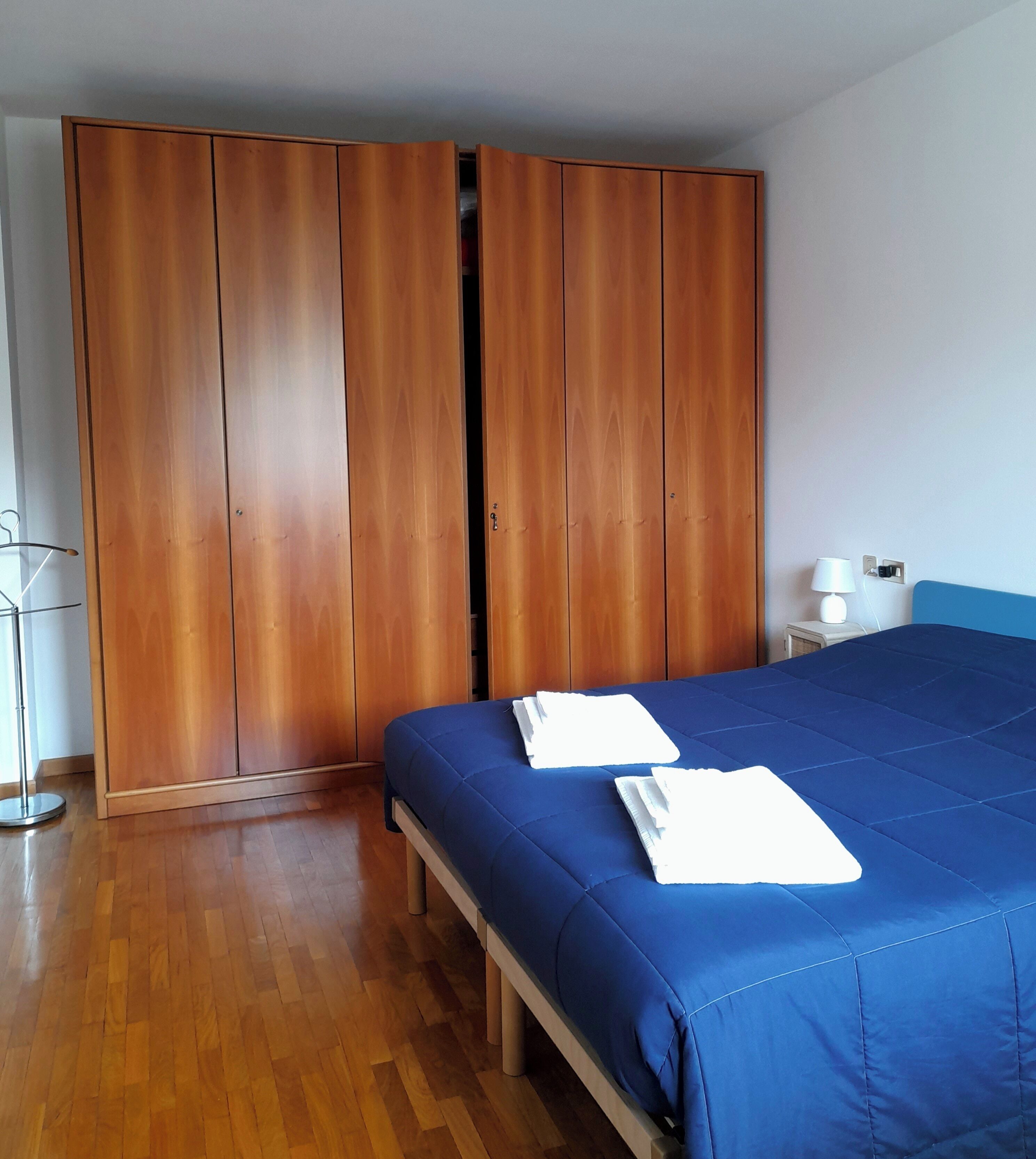Quarto com cama, guarda-roupa e mesa de cabeceira.