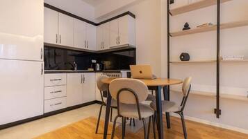 Uma cozinha moderna com armários brancos, uma mesa de jantar de madeira e cadeiras.