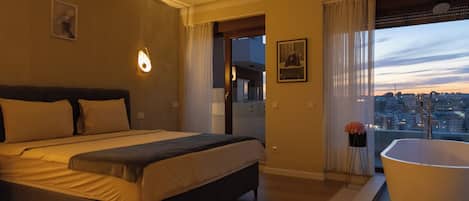 Quarto de hotel com cama grande, banheira e vista para a cidade pela janela.