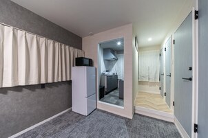 Quarto compacto com cozinha compacta, guarda-roupa e espelho.