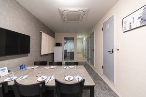 Uma sala de conferência com uma mesa grande, cadeiras, uma TV de tela plana e uma porta com uma placa.