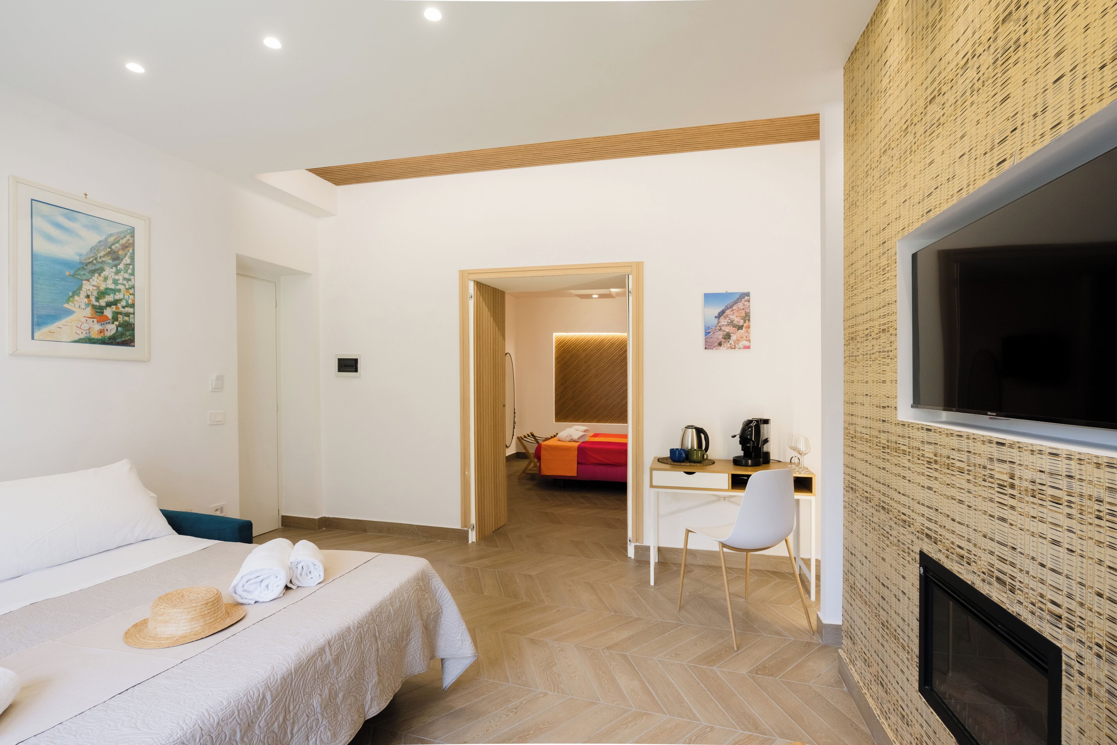 Quarto de hotel com cama, escrivaninha, televisão e lareira.