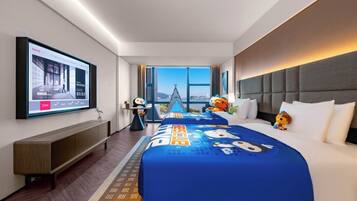 Quarto de hotel com uma cama grande, televisão na parede, vista para a cidade e uma janela.